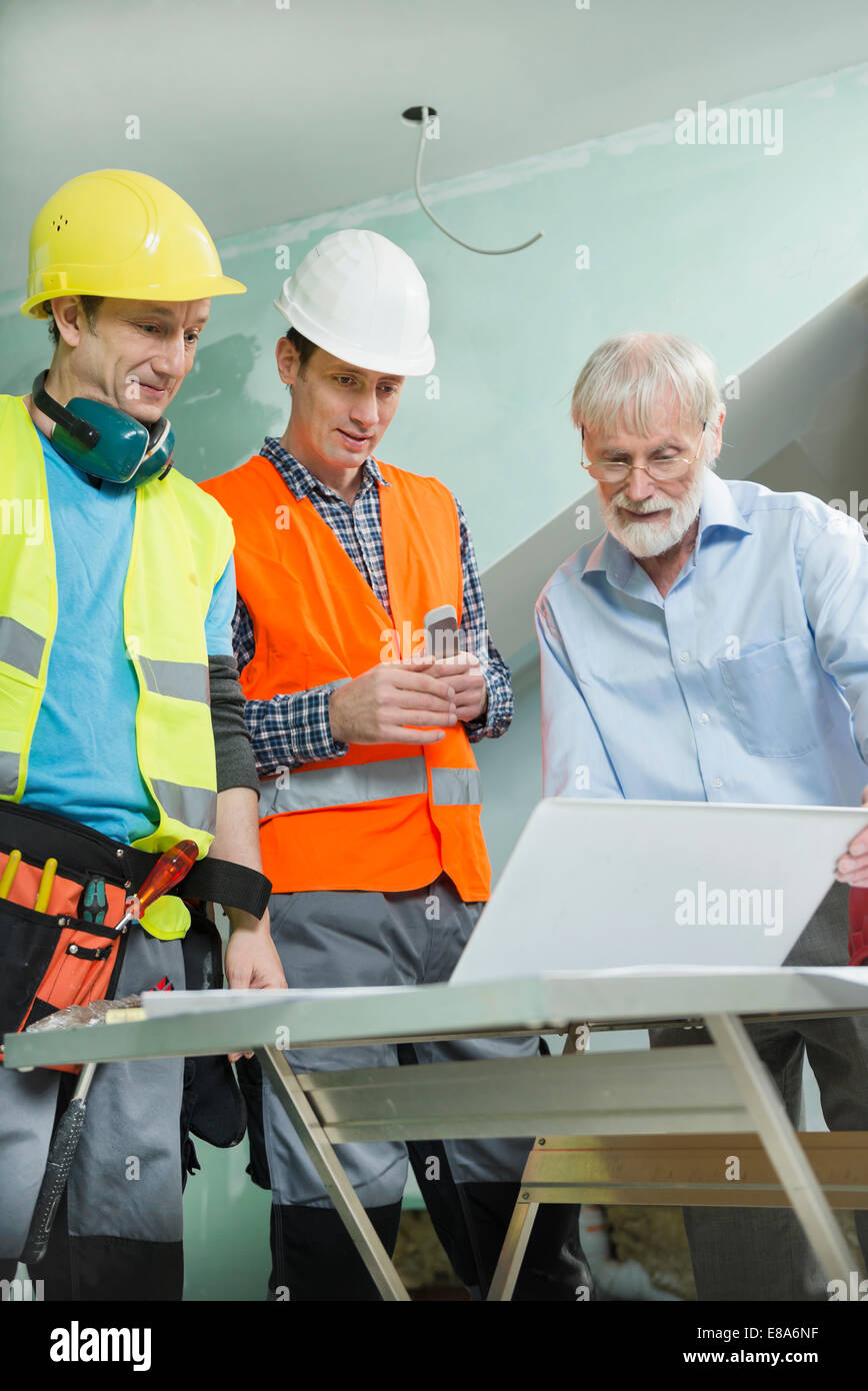 Architect and two construction workers at construction site of new ...