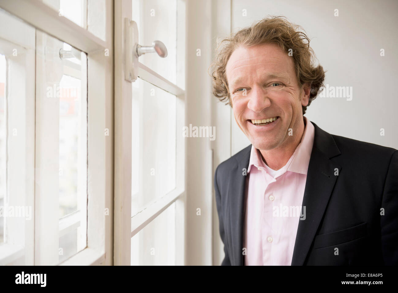 Smiling man in suit at the window Stock Photo - Alamy
