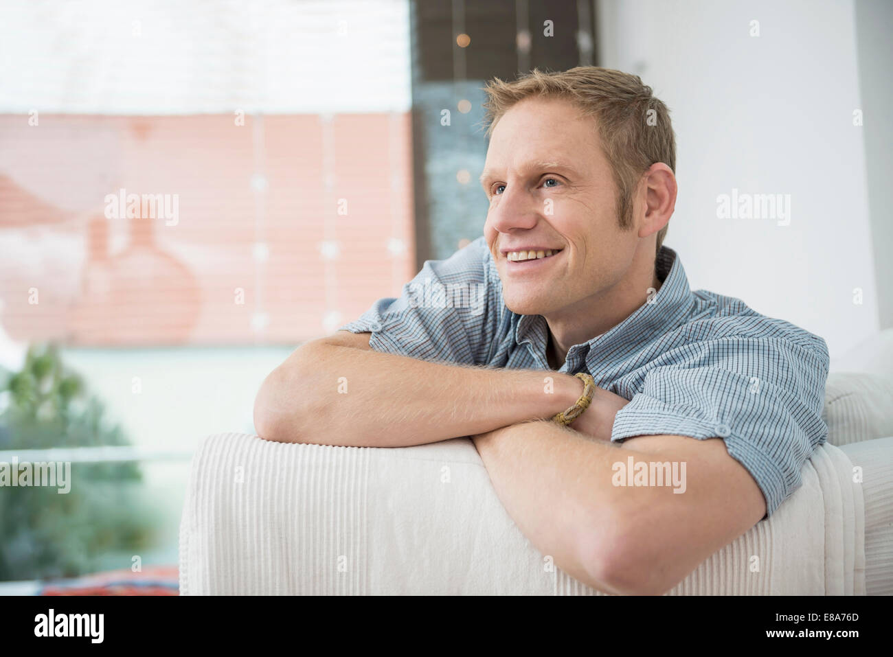 Man sitting on sofa, smiling Stock Photo - Alamy