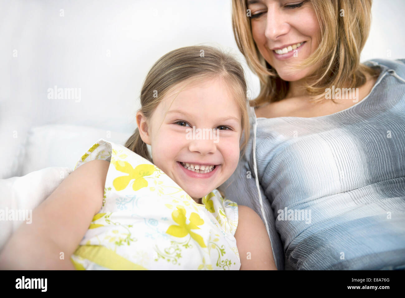 Mother and daughter sitting on sofa, smiling Stock Photo - Alamy