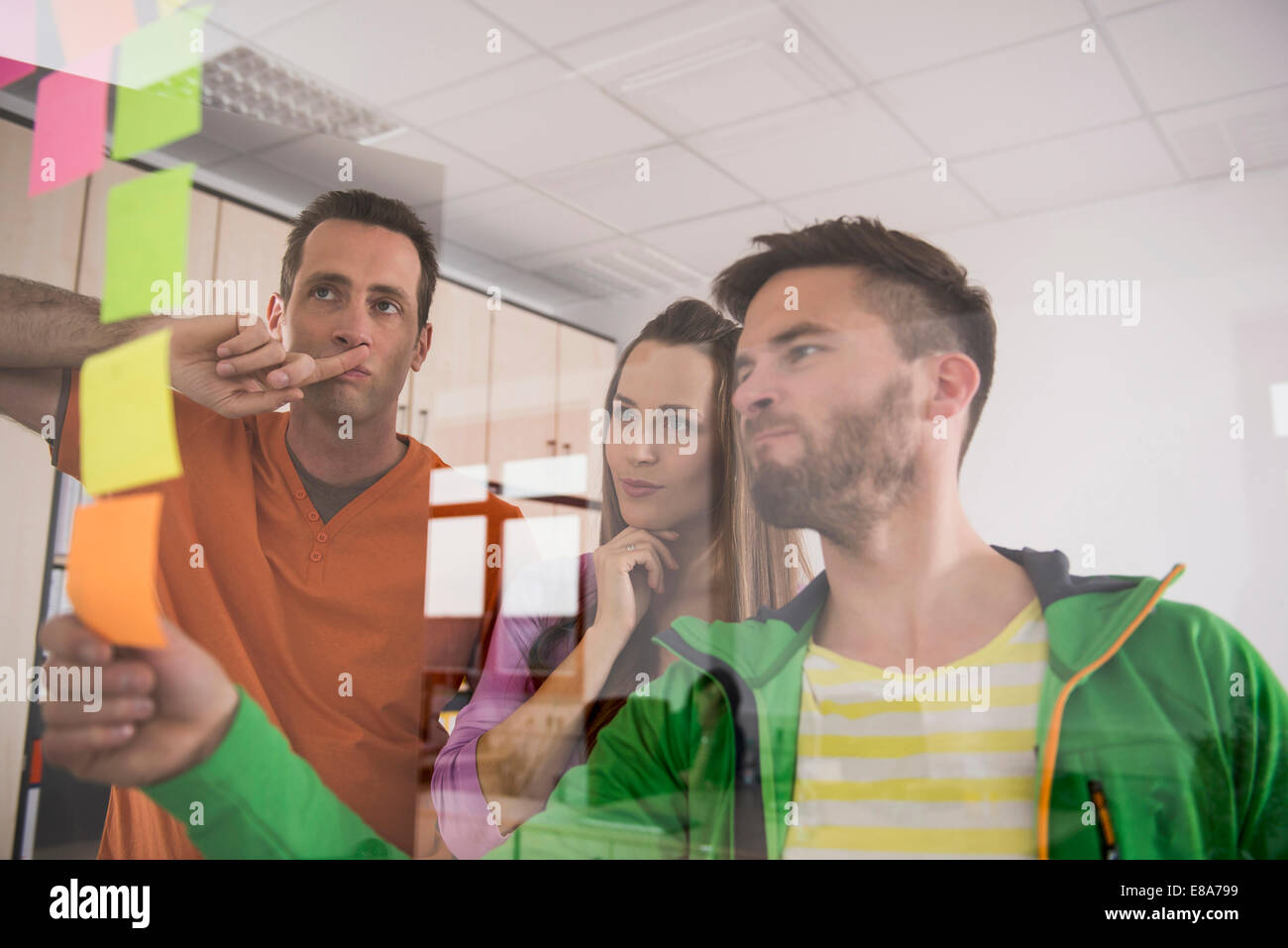 Young colleagues brainstorming sticking post-its Stock Photo - Alamy