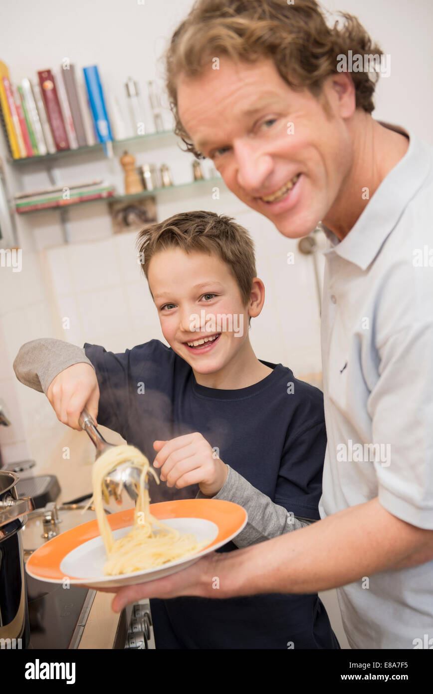 Father and son eating spaghetti in kitchen Stock Photo - Alamy