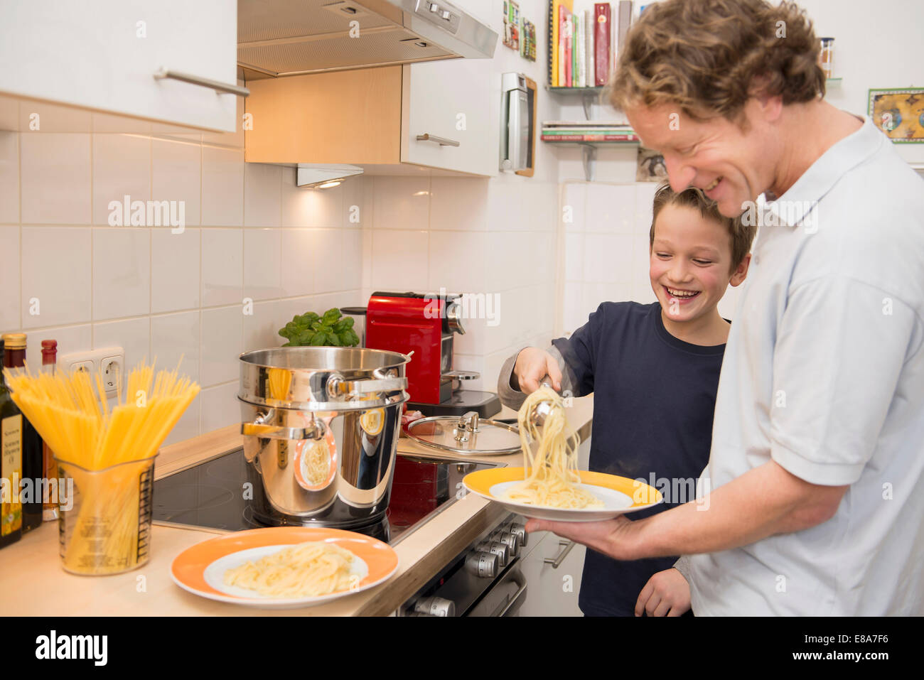 Father and son eating spaghetti in kitchen Stock Photo - Alamy