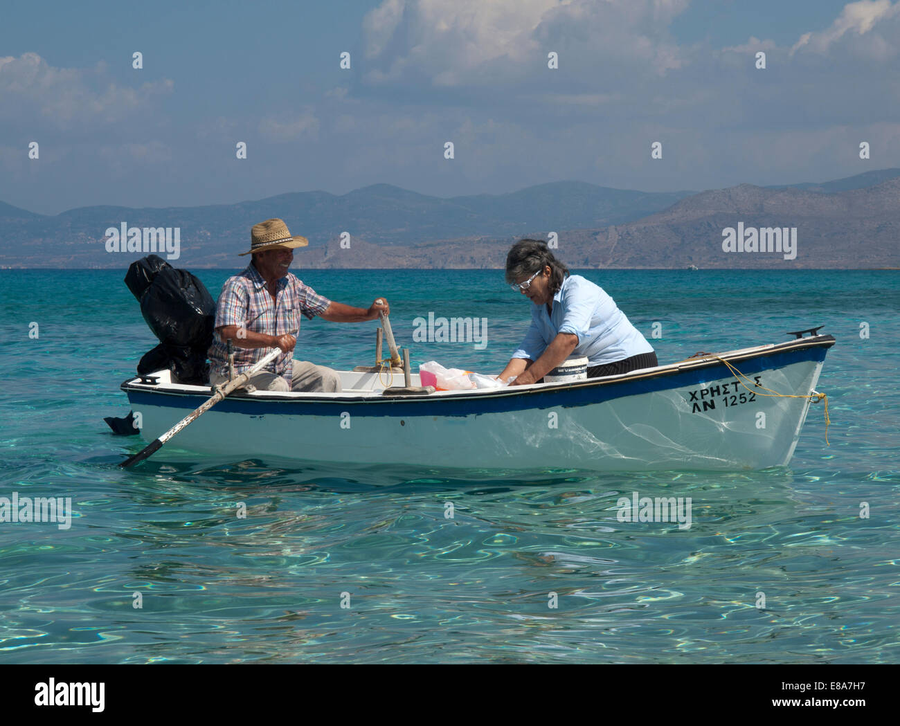 A Greek couple do some fishing on their boat off the island of ...