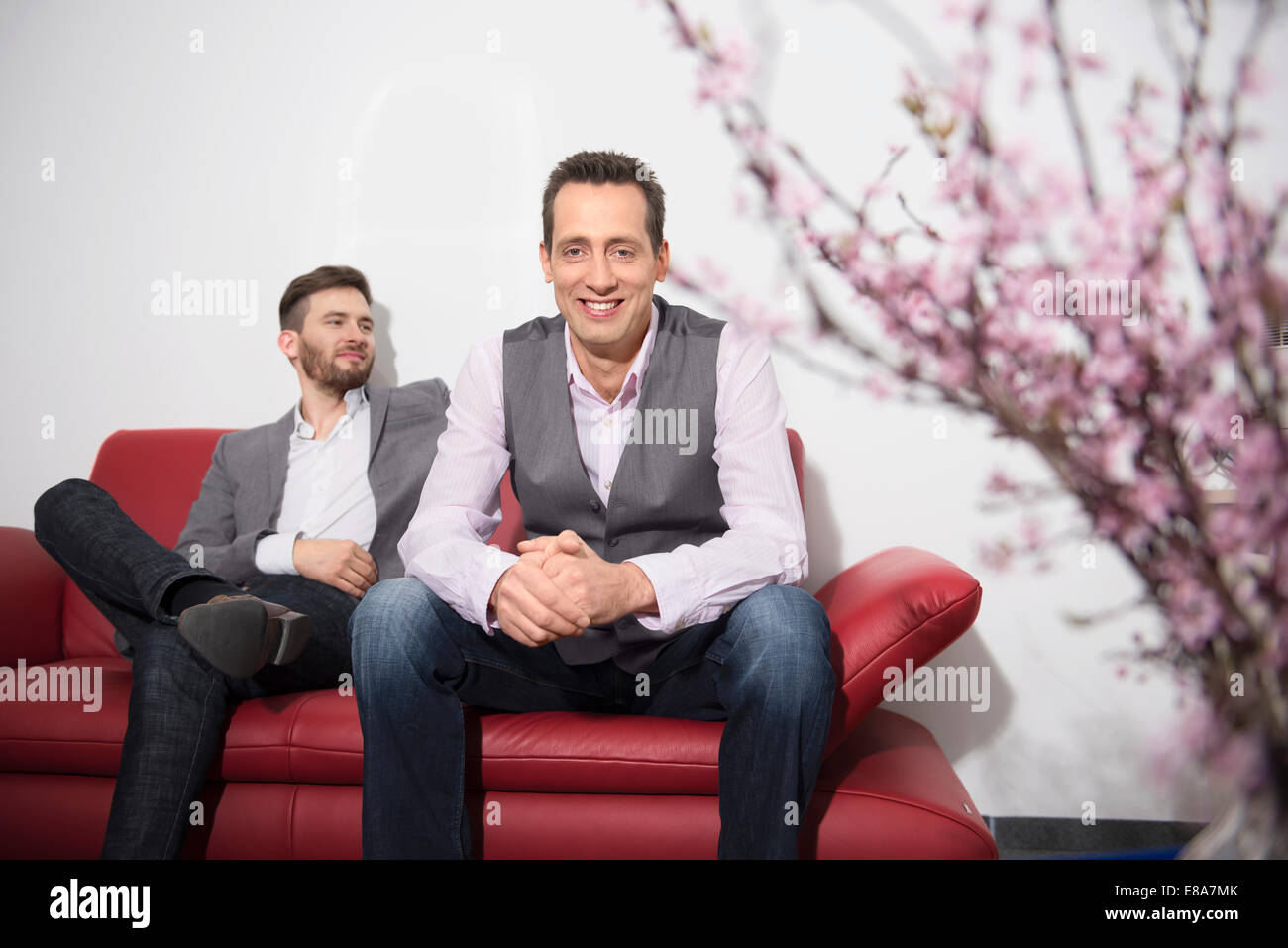 Two young men sitting on sofa waiting Stock Photo - Alamy Two young men sitting on sofa waiting Stock Photo - Alamy