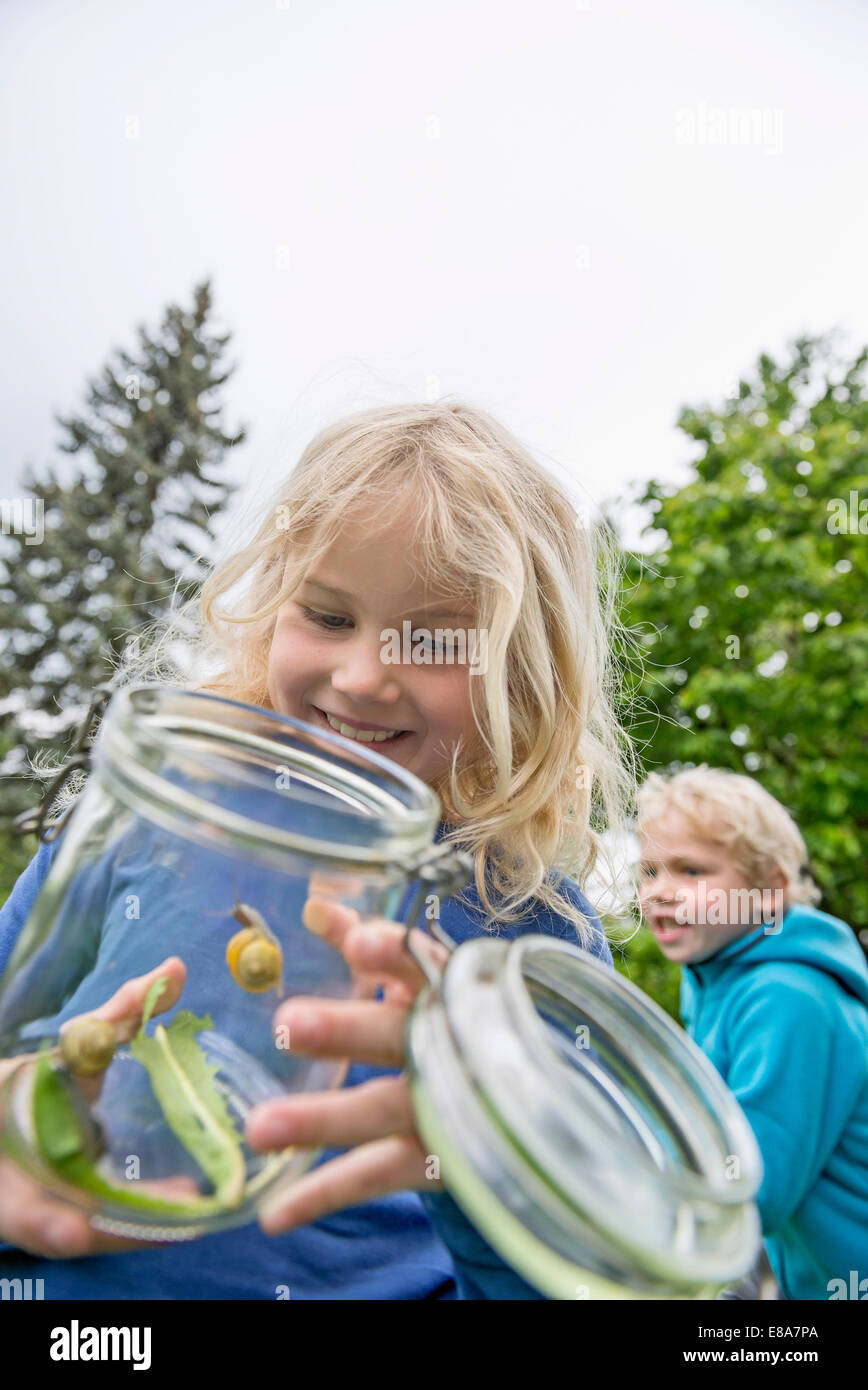 Young blonde girl collecting snails in jam-jar Stock Photo - Alamy