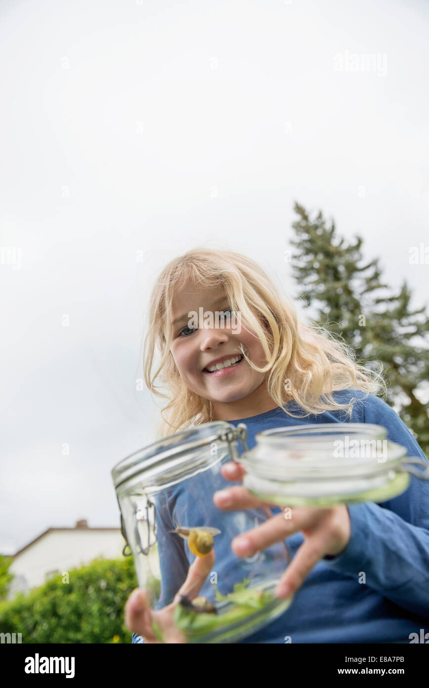 Young blonde girl collecting snails in jam-jar Stock Photo - Alamy