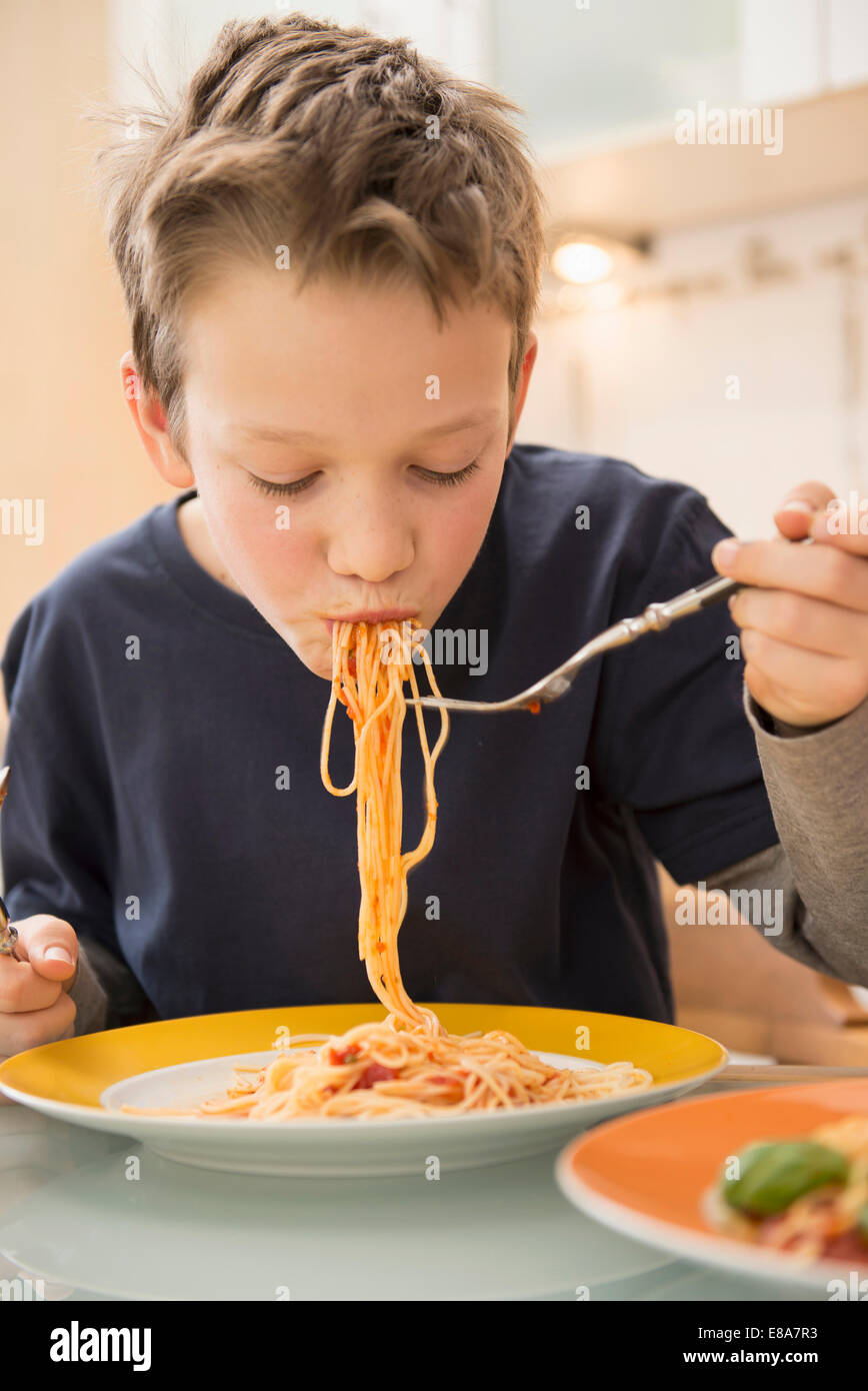 Boy eating spaghetti in kitchen Stock Photo - Alamy