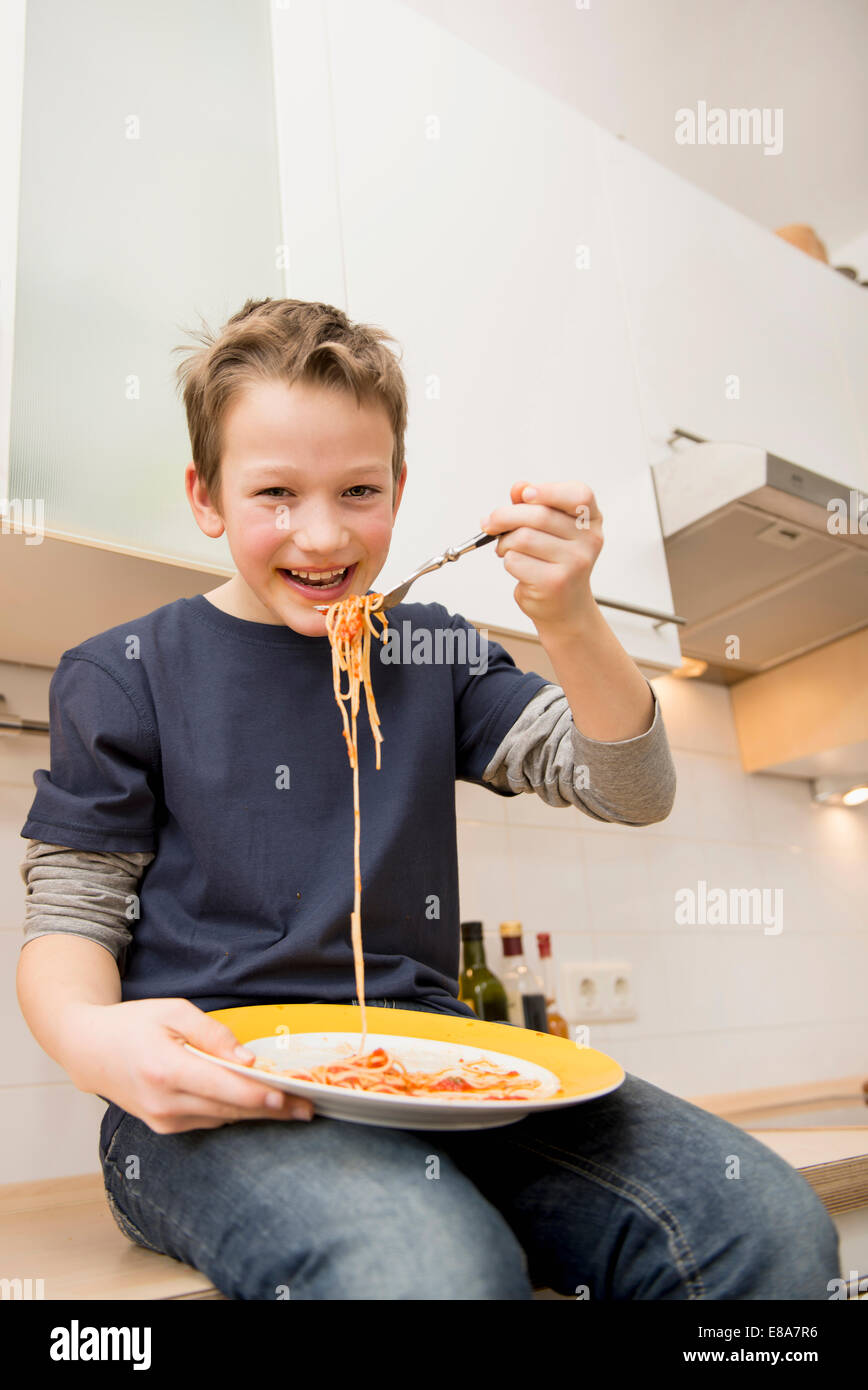 Boy eating spaghetti on kitchen counter Stock Photo - Alamy