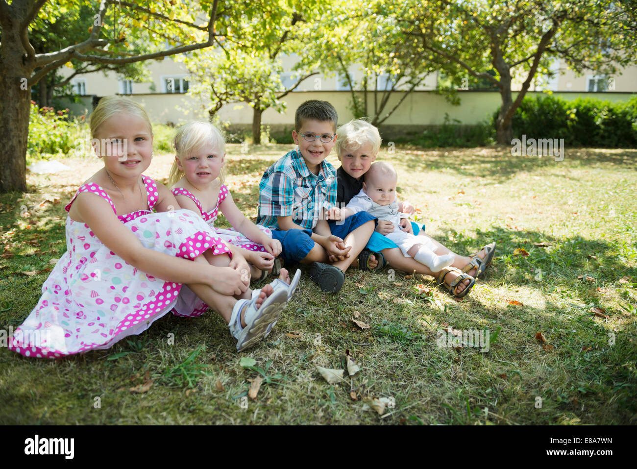 Five children sitting on meadow Stock Photo - Alamy