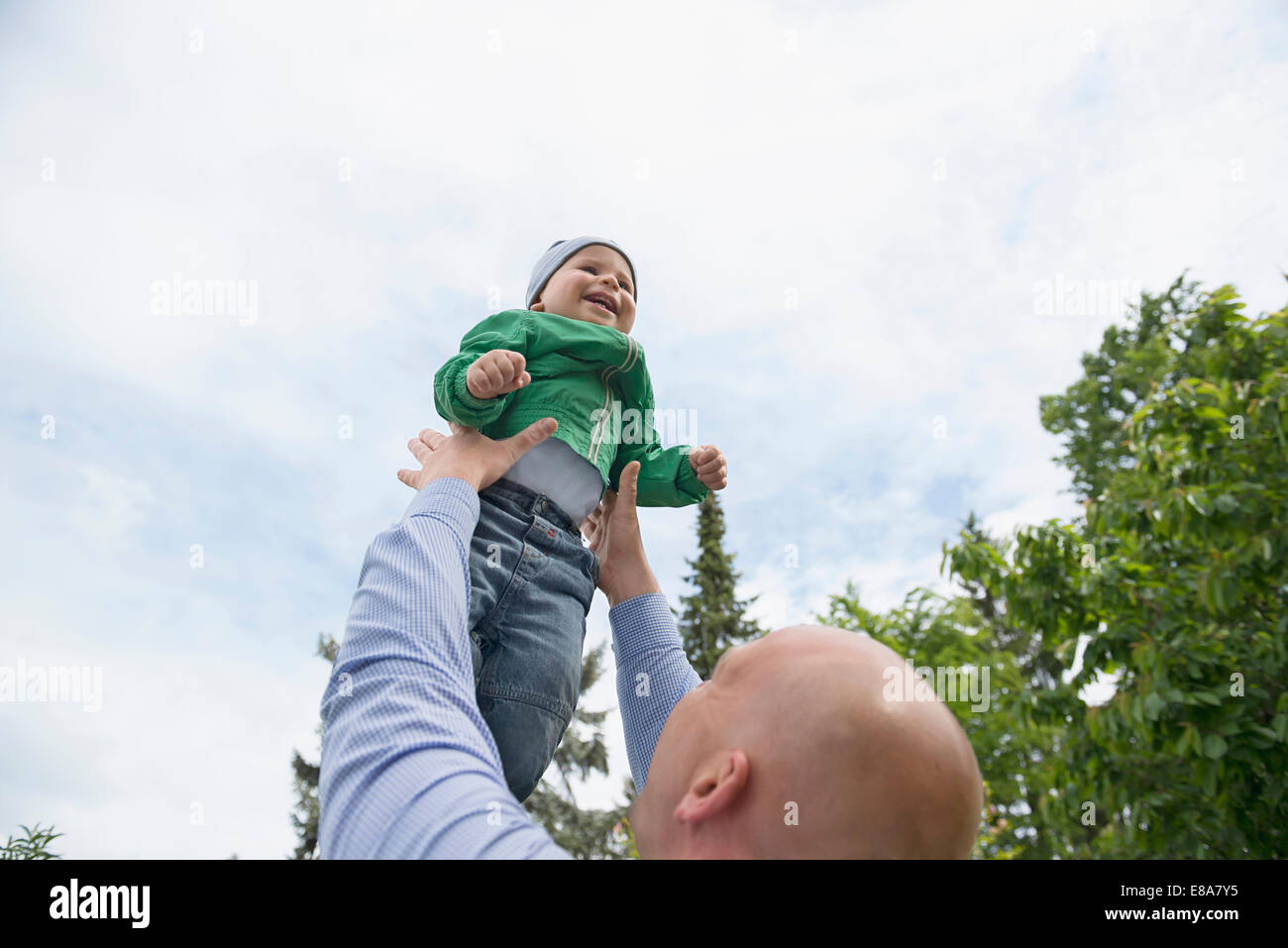 Father holding baby boy in arms playing flying Stock Photo - Alamy