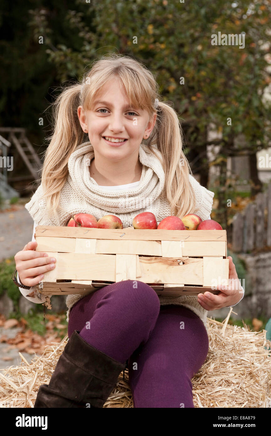 Blond girl holding crate with apples Stock Photo - Alamy