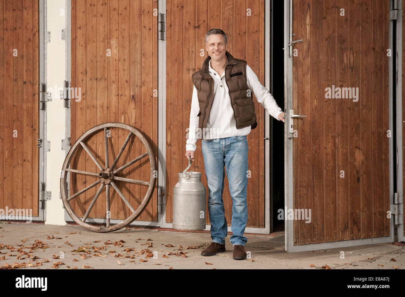 Smiling man holding milk churn on farm Stock Photo - Alamy