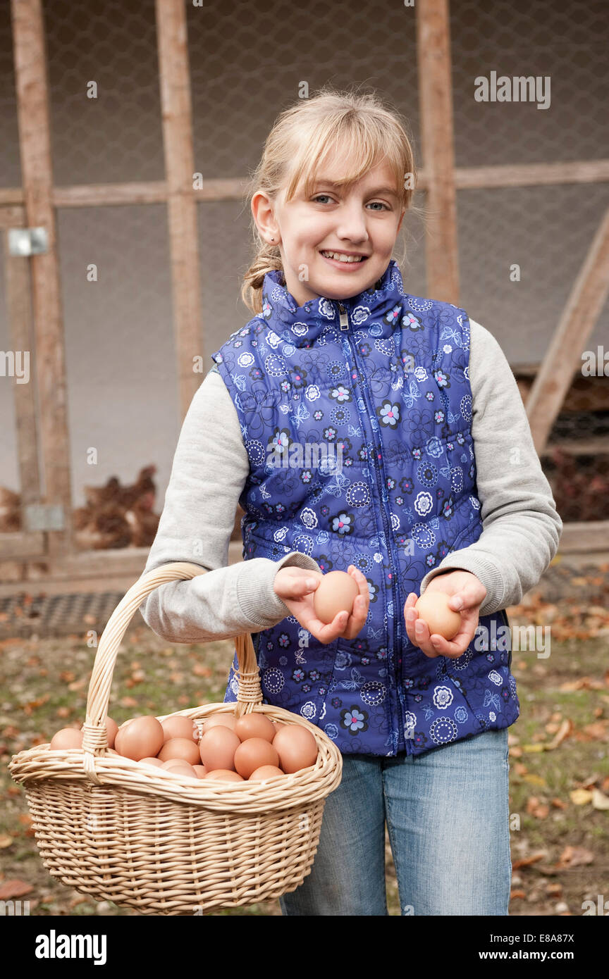 Blond girl holding basket with eggs on farm Stock Photo - Alamy
