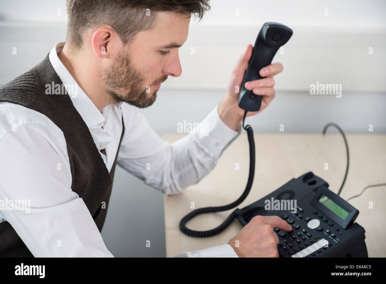 Manager in office dialing landline telephone Stock Photo - Alamy