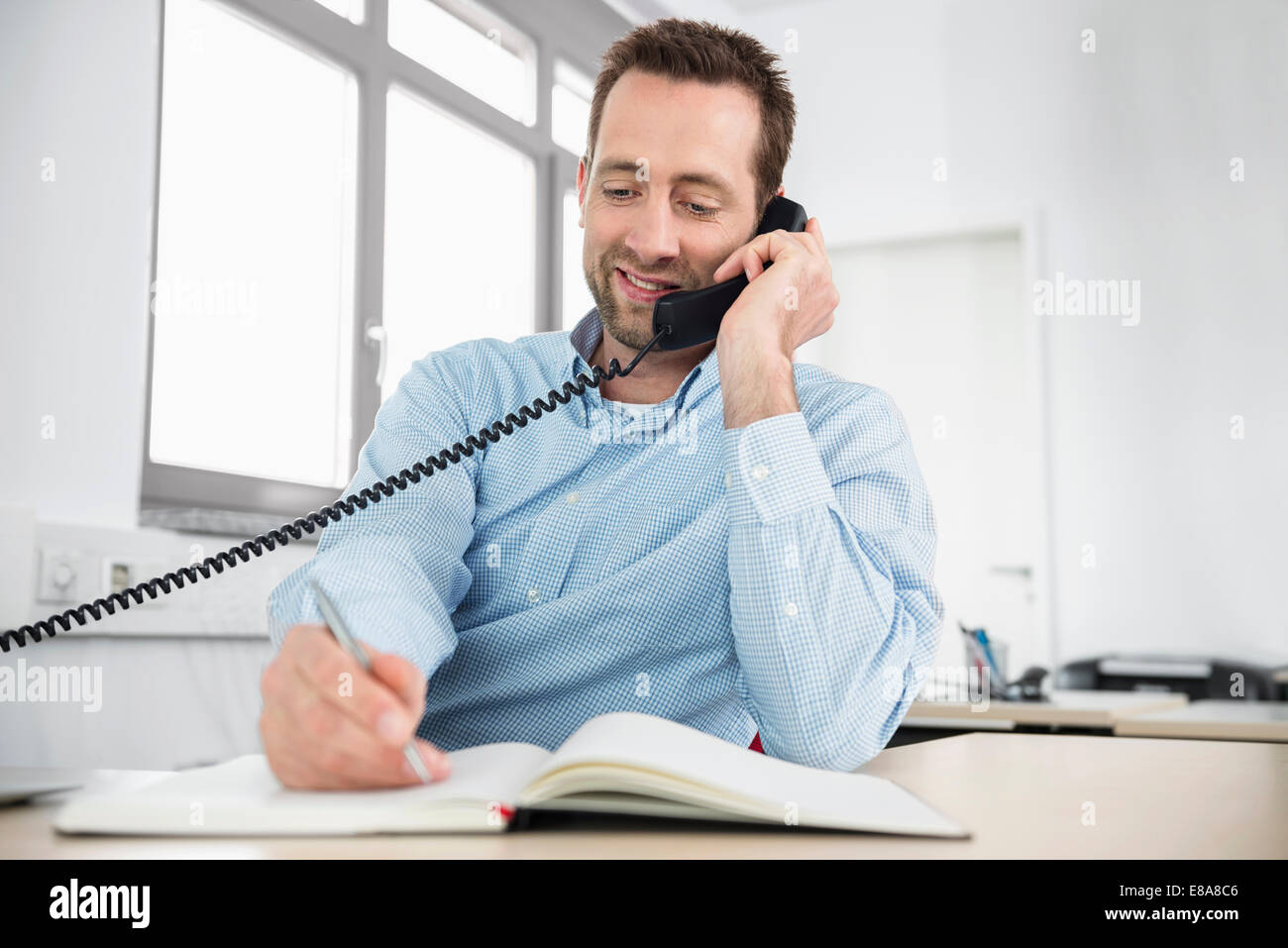 Man office landline telephone writing memo Stock Photo - Alamy