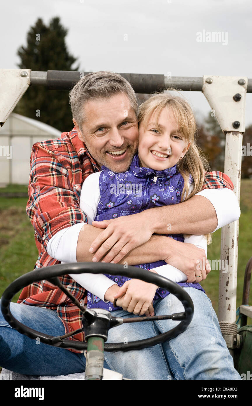 Farmer hugging daughter on tractor Stock Photo - Alamy