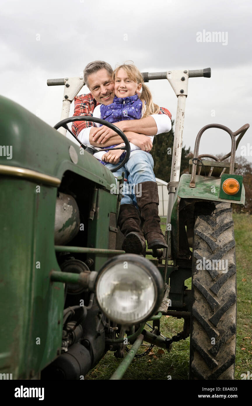 Farmer hugging daughter on tractor Stock Photo - Alamy