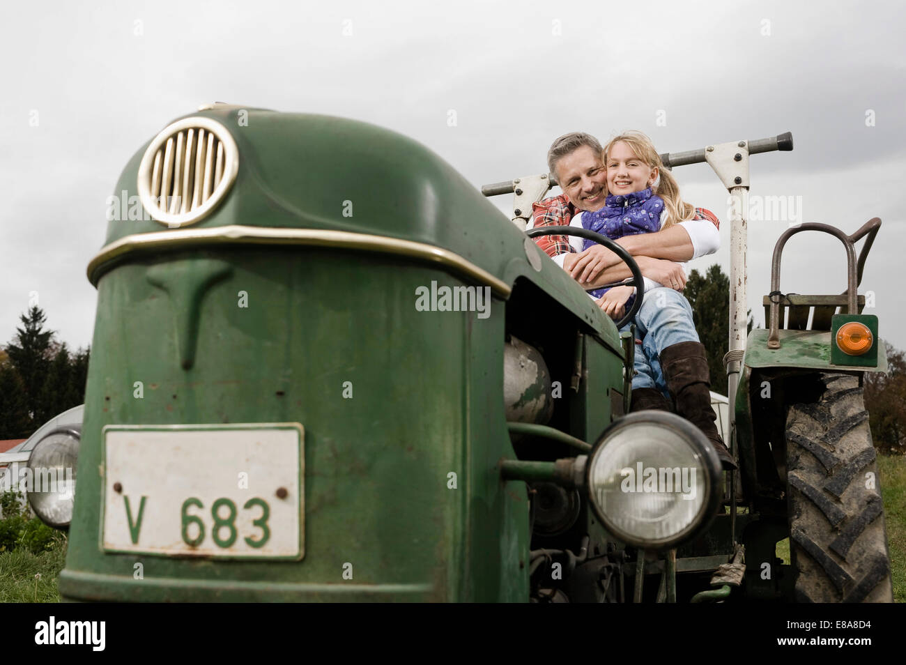 Farmer hugging daughter on tractor Stock Photo - Alamy