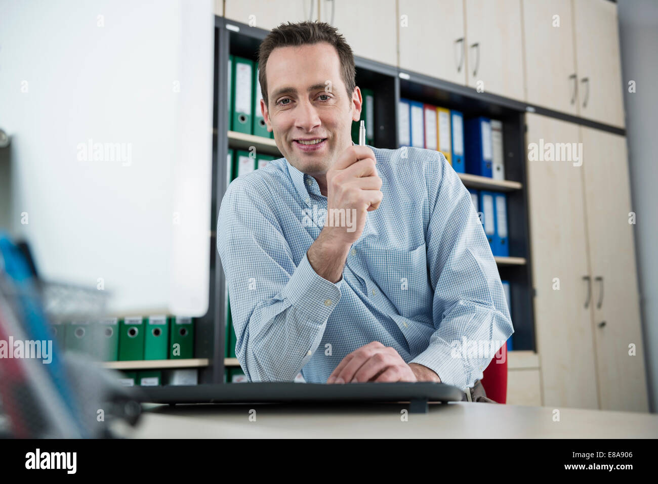 Young man sitting in office working at computer Stock Photo - Alamy