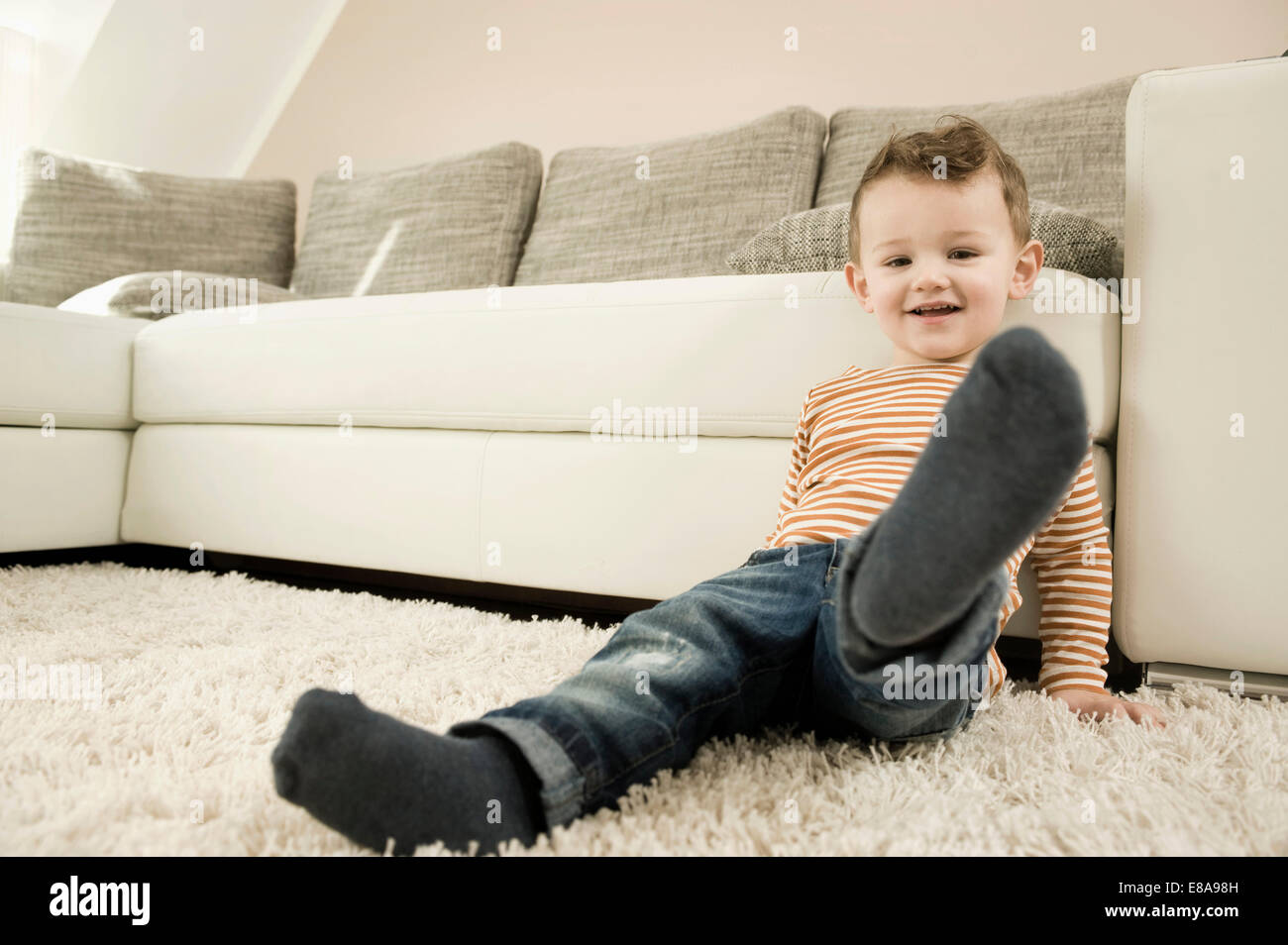 Portrait of boy sitting on rug, smiling Stock Photo - Alamy