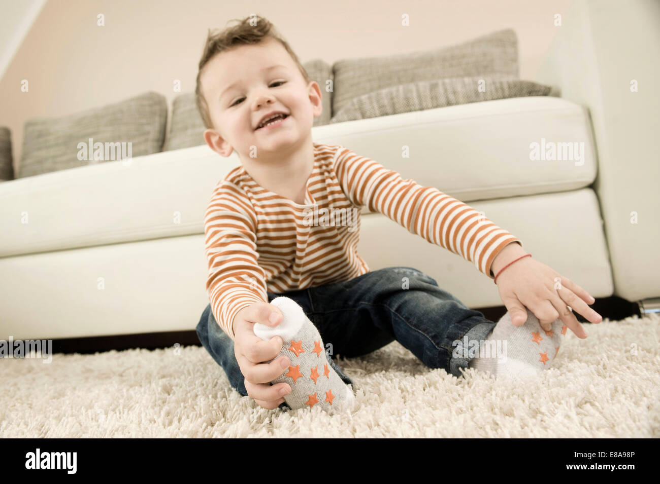 Portrait of boy sitting on rug, smiling Stock Photo - Alamy