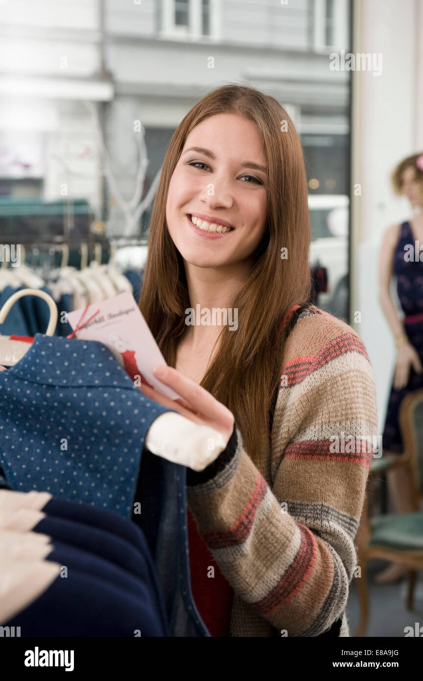 Portrait of young woman shopping in fashion store, smiling Stock Photo ...