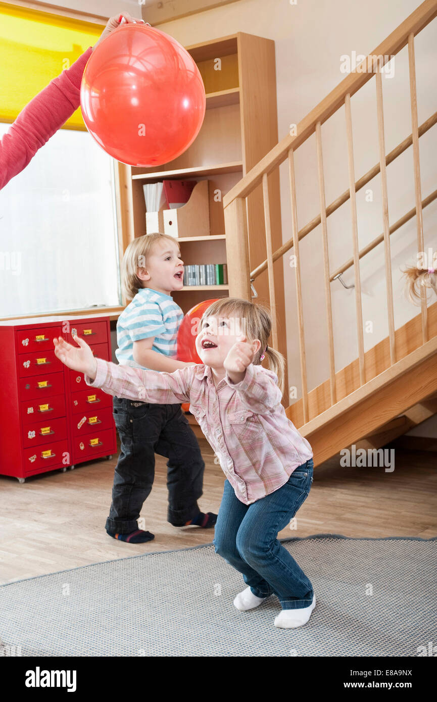 Two kids playing with red balloons in kindergarten Stock Photo - Alamy
