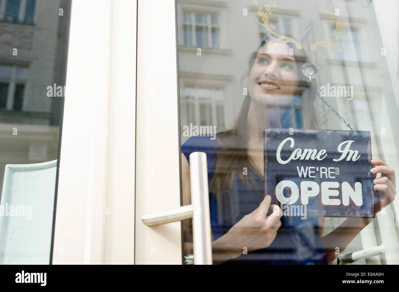 Sales girl holding opening board of fashion shop, smiling Stock Photo ...