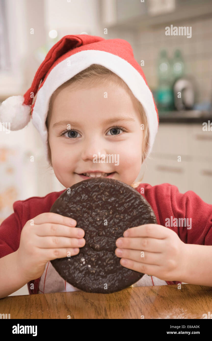 Girl eating gingerbread cookie, smiling, portrait Stock Photo - Alamy