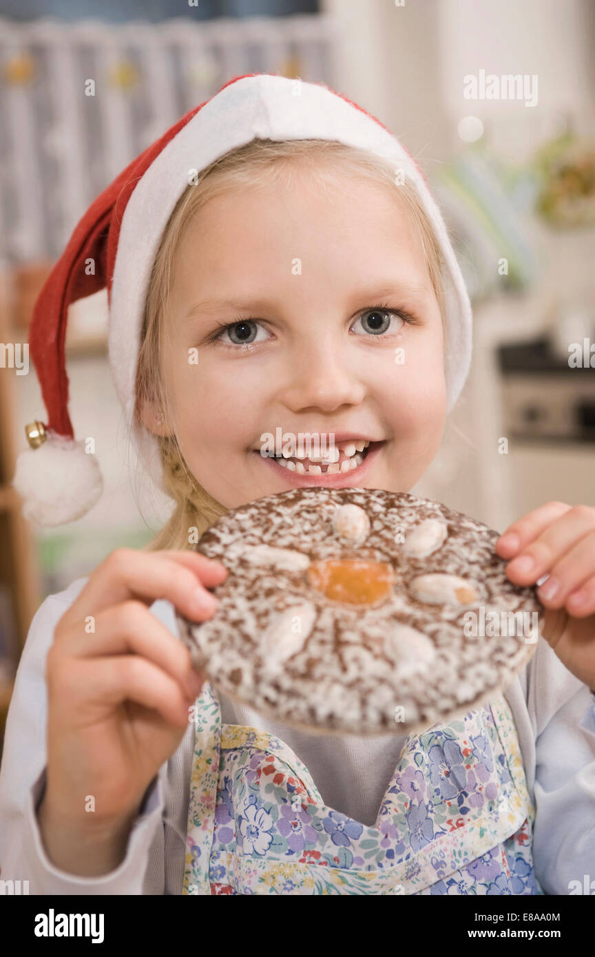 Girl eating gingerbread cookie, smiling, portrait Stock Photo - Alamy