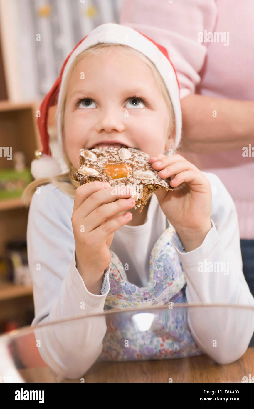 Girl eating gingerbread, looking up Stock Photo - Alamy