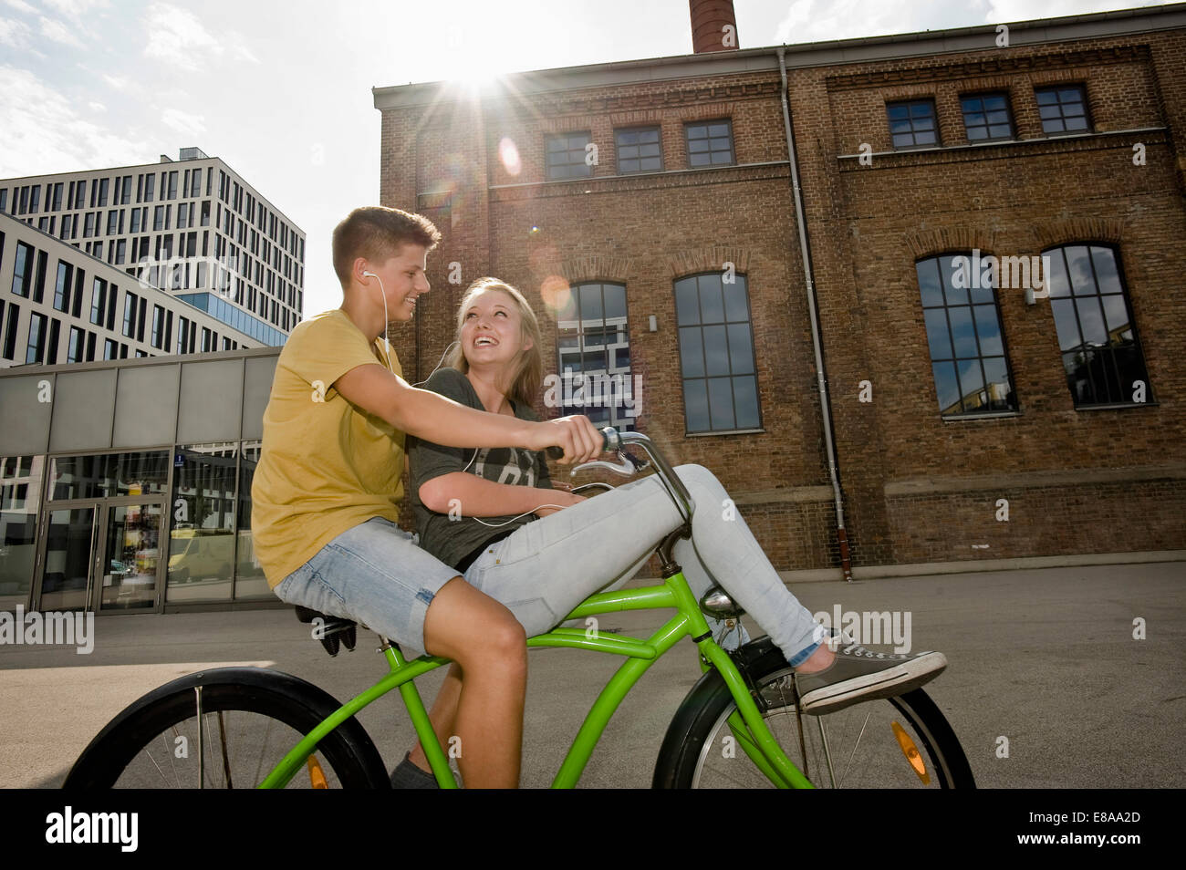 Teenage couple listening music on bicycle, smiling Stock Photo - Alamy