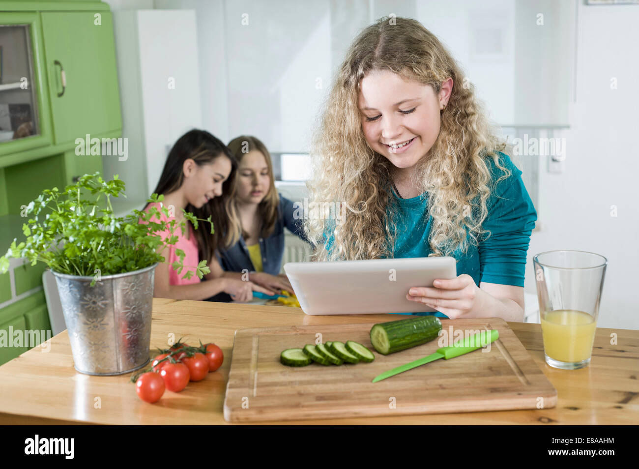 Girls in kitchen with digital tablet, preparing vegetables Stock Photo ...