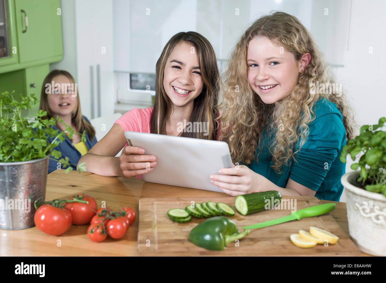 Girls in kitchen with digital tablet, preparing vegetables Stock Photo ...