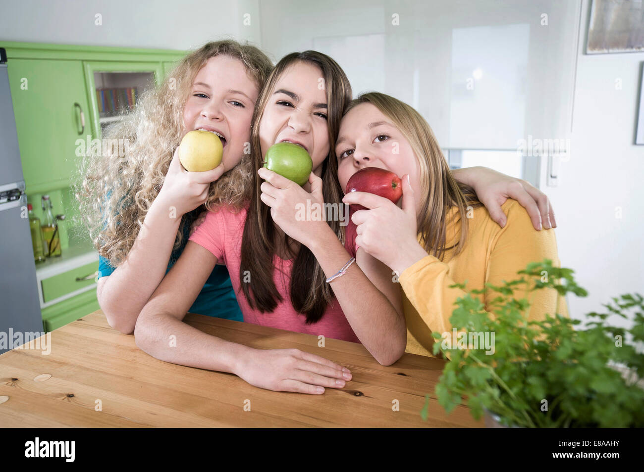 Girls in kitchen eating apples Stock Photo - Alamy