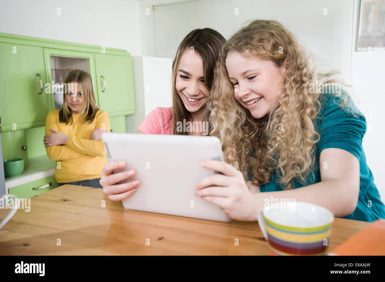 Girls in kitchen excluding friend Stock Photo - Alamy