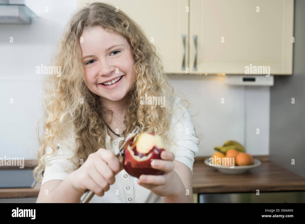 Girl in kitchen peeling apple Stock Photo - Alamy