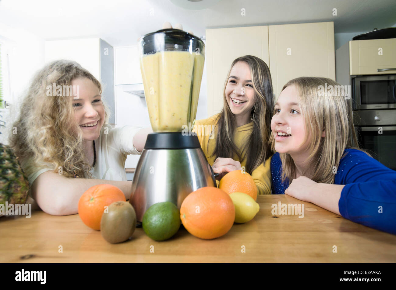 Girls in kitchen preparing fruit smoothie Stock Photo - Alamy