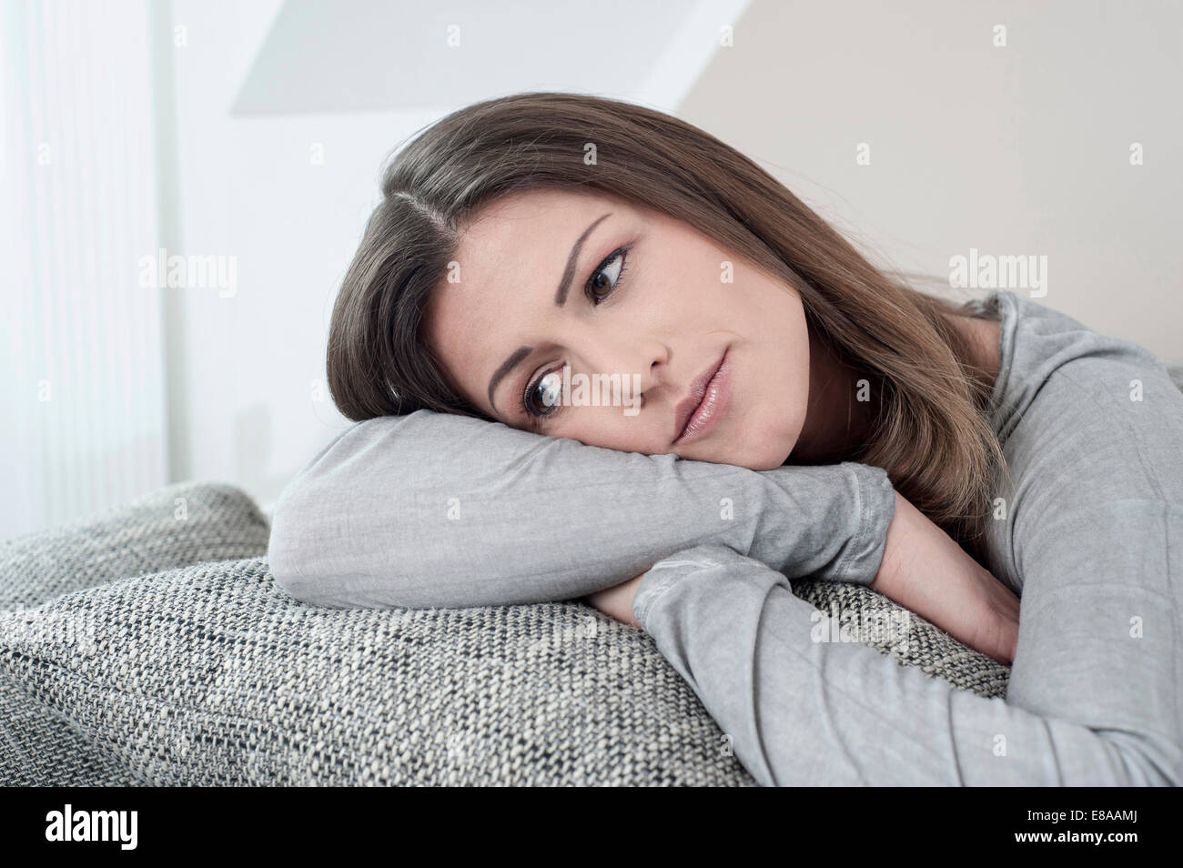 Portrait of pensive young woman on couch at home Stock Photo - Alamy