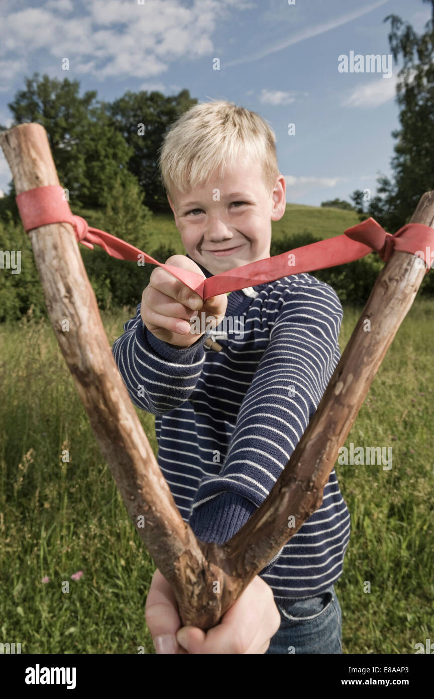 Young boy holding wooden slingshot smiling Stock Photo - Alamy