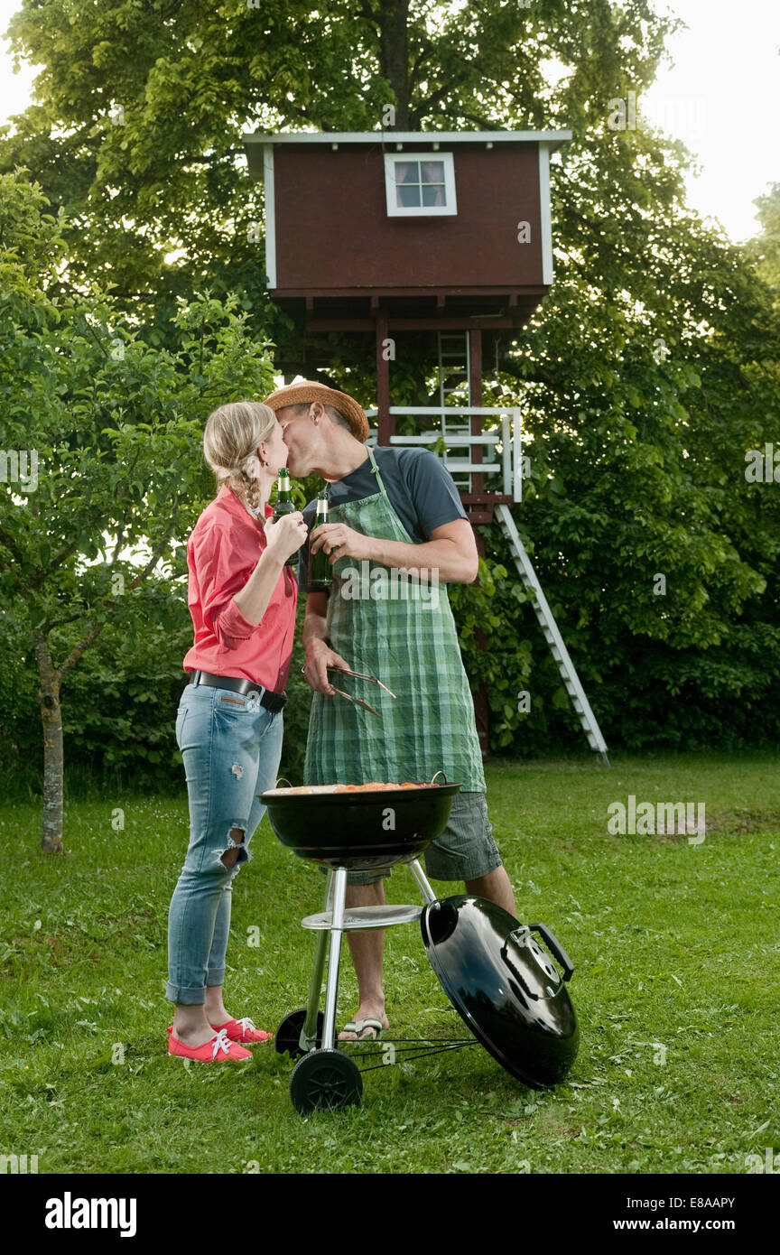 Young couple barbecue grill garden beer kissing Stock Photo - Alamy