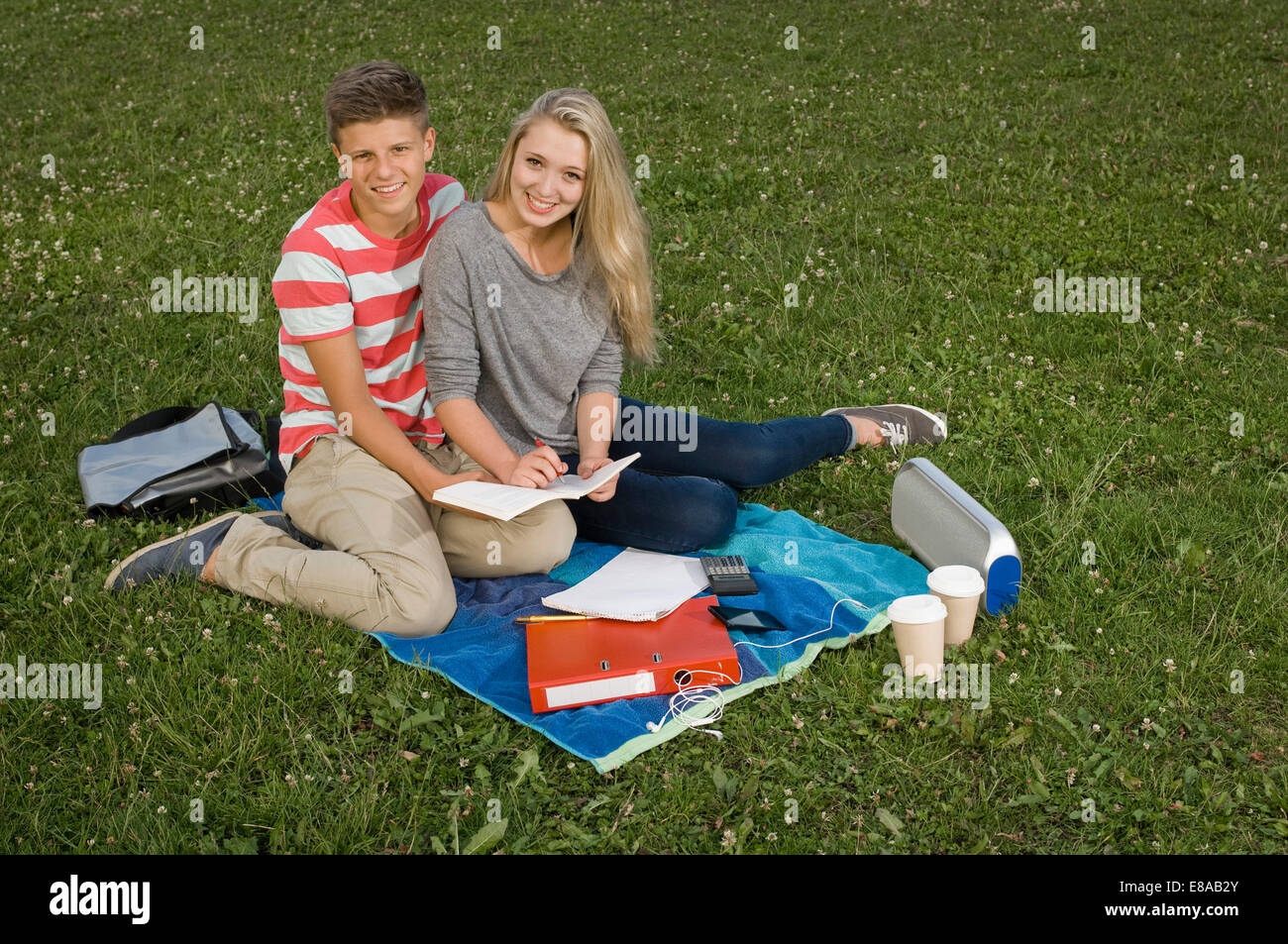 Portrait of teenage couple doing homework in park, smiling Stock Photo ...