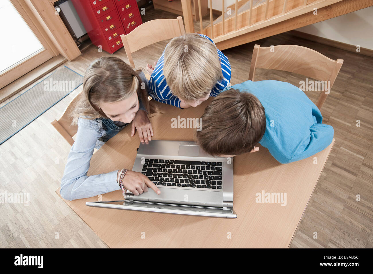 Three children looking at laptop Stock Photo - Alamy