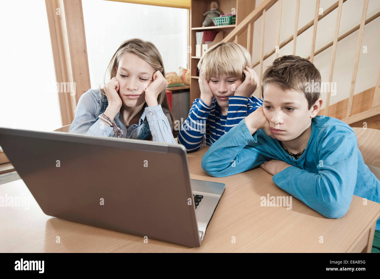 Three boring children looking at laptop Stock Photo - Alamy