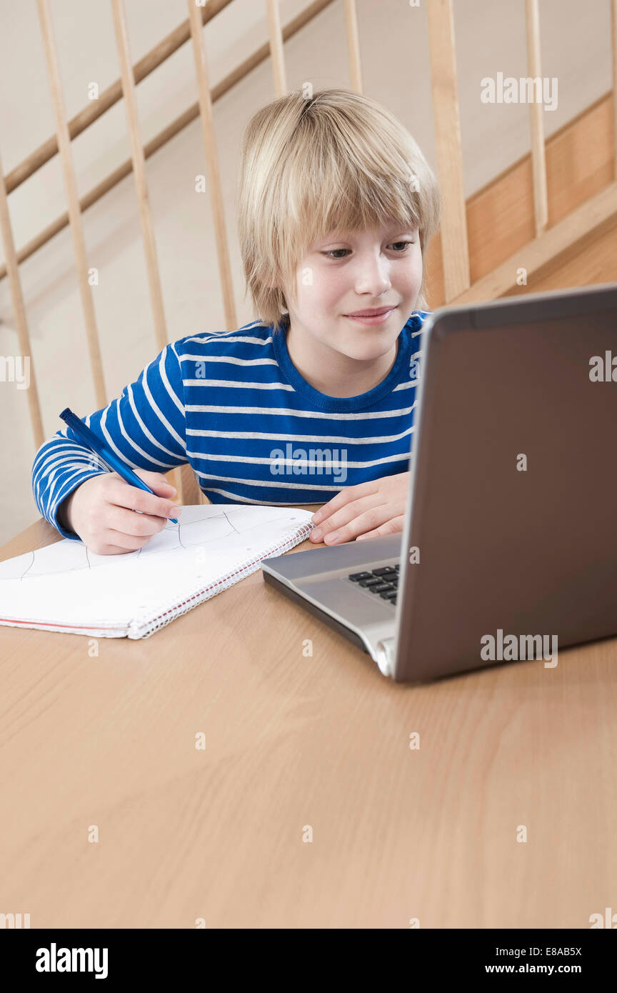 Boy using laptop for doing his homework Stock Photo - Alamy