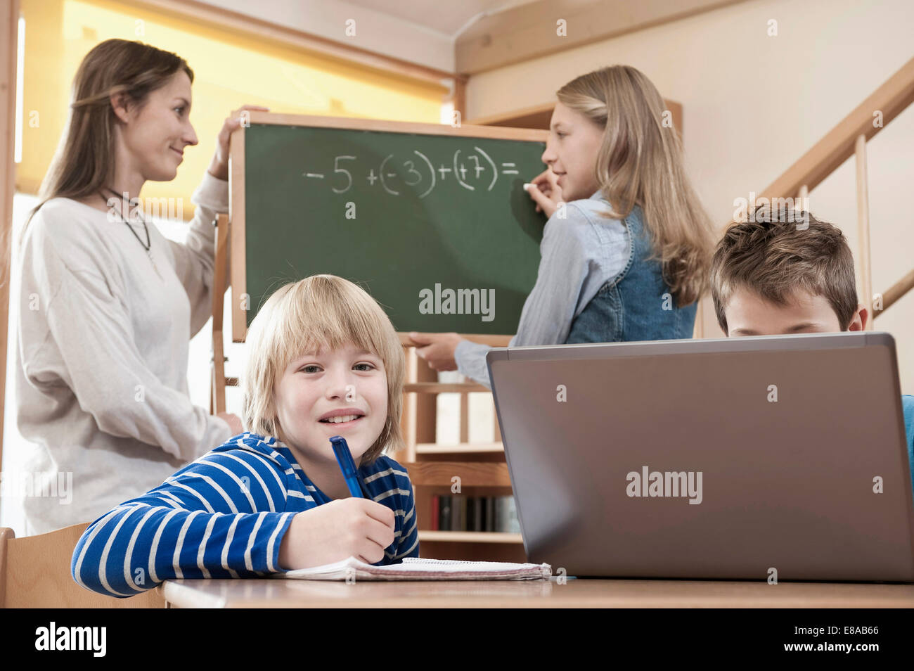 Female childcare assistant helping children by doing homework Stock ...