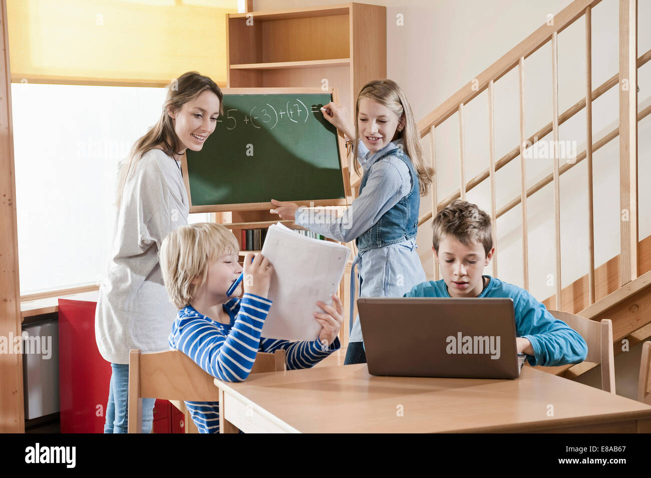 Female childcare assistant helping children by doing homework Stock ...