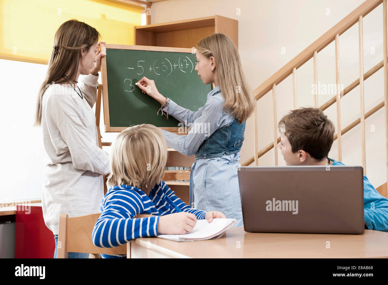 Female childcare assistant helping children by doing homework Stock ...