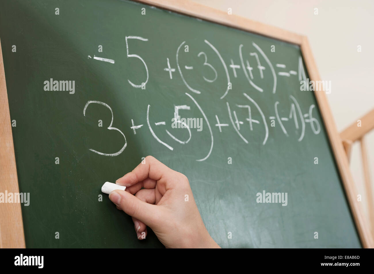 Girl writing arithmetic problem on blackboard Stock Photo - Alamy